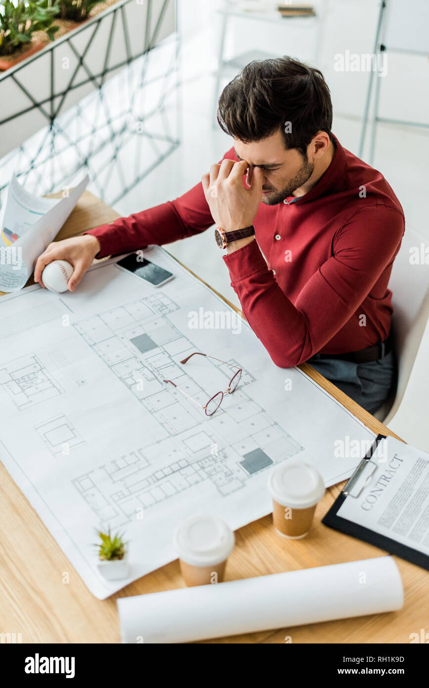 stressed male architect having headache while working on blueprint in ...