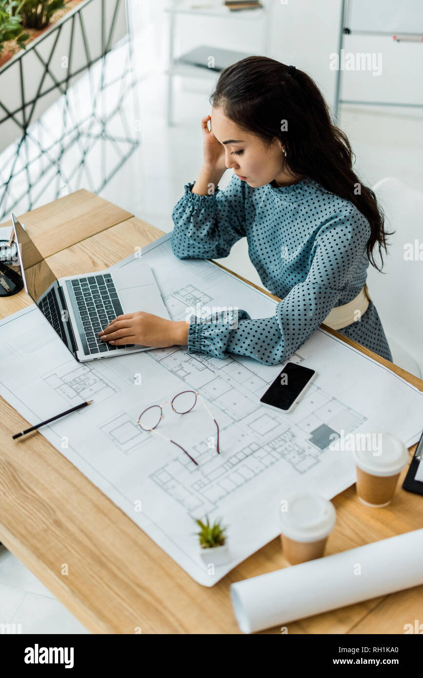 stressed asian female architect having headache while using laptop in ...
