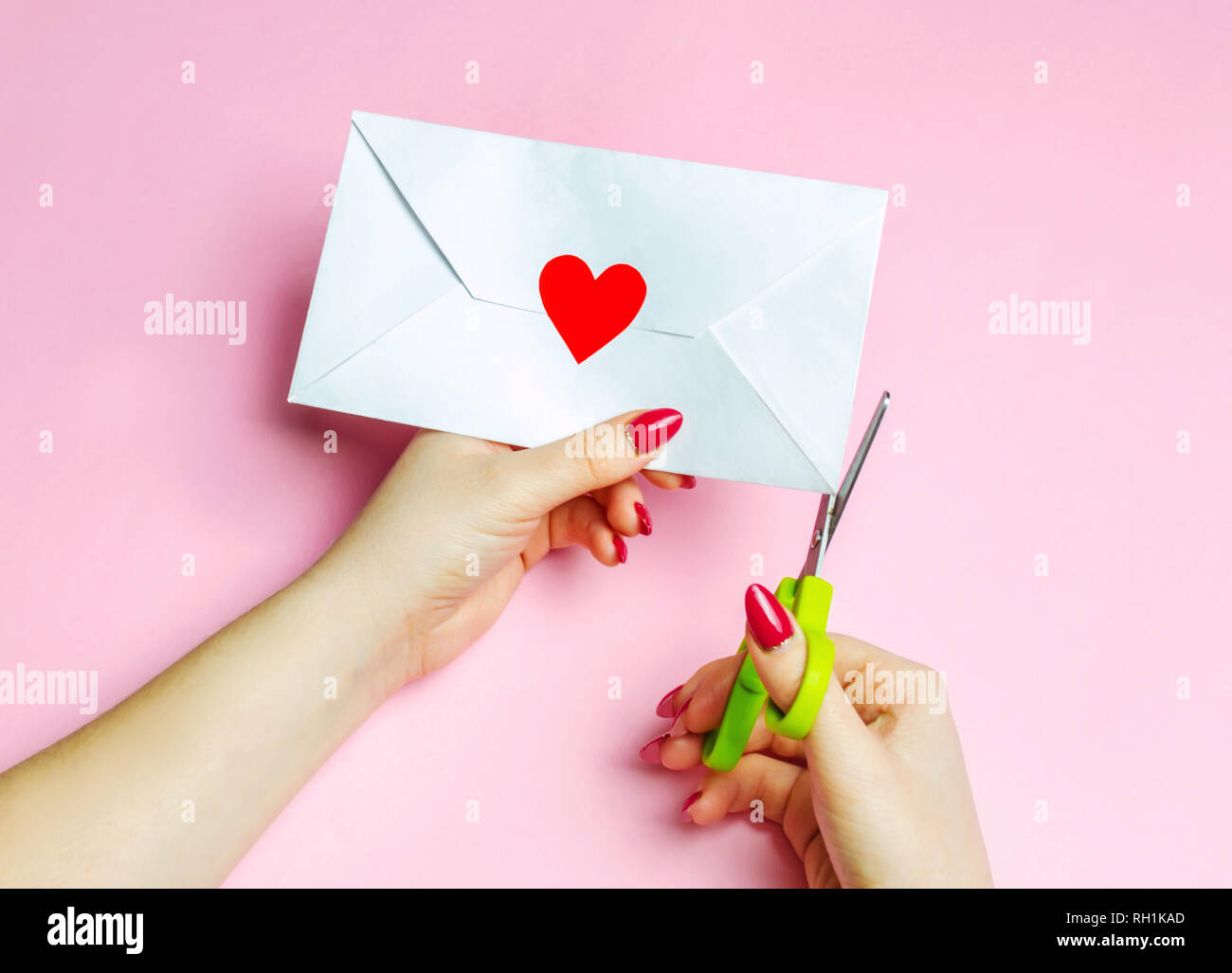 Female hand opens envelope with a red heart. A love letter to the ...