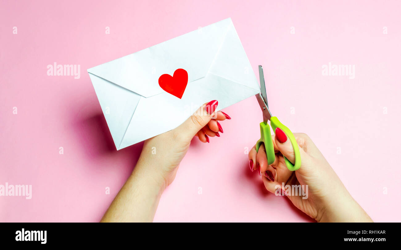 Female hand opens envelope with a red heart. A love letter to the ...