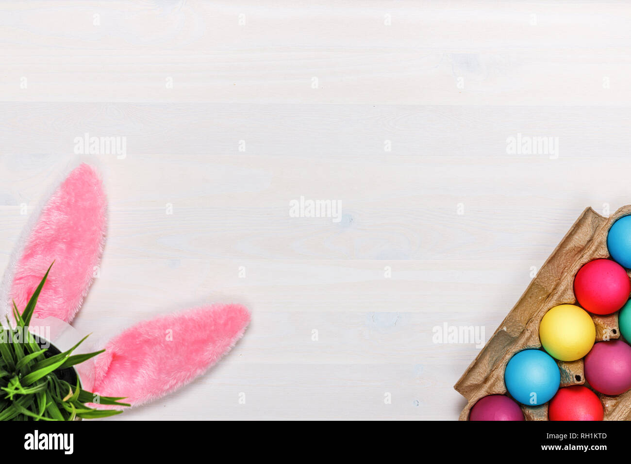 Rabbit ears, a flower pot with artificial green grass, colorful eggs in ...