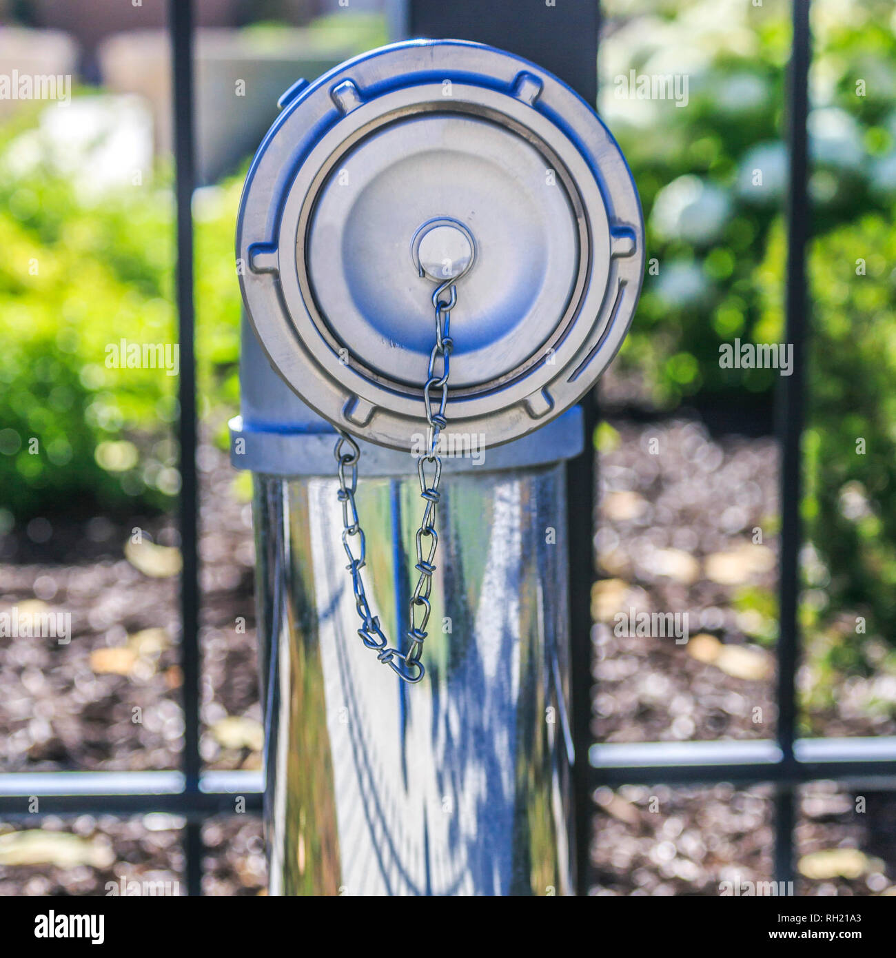 Metal fire hydrant against a fence on a sunny day Stock Photo - Alamy