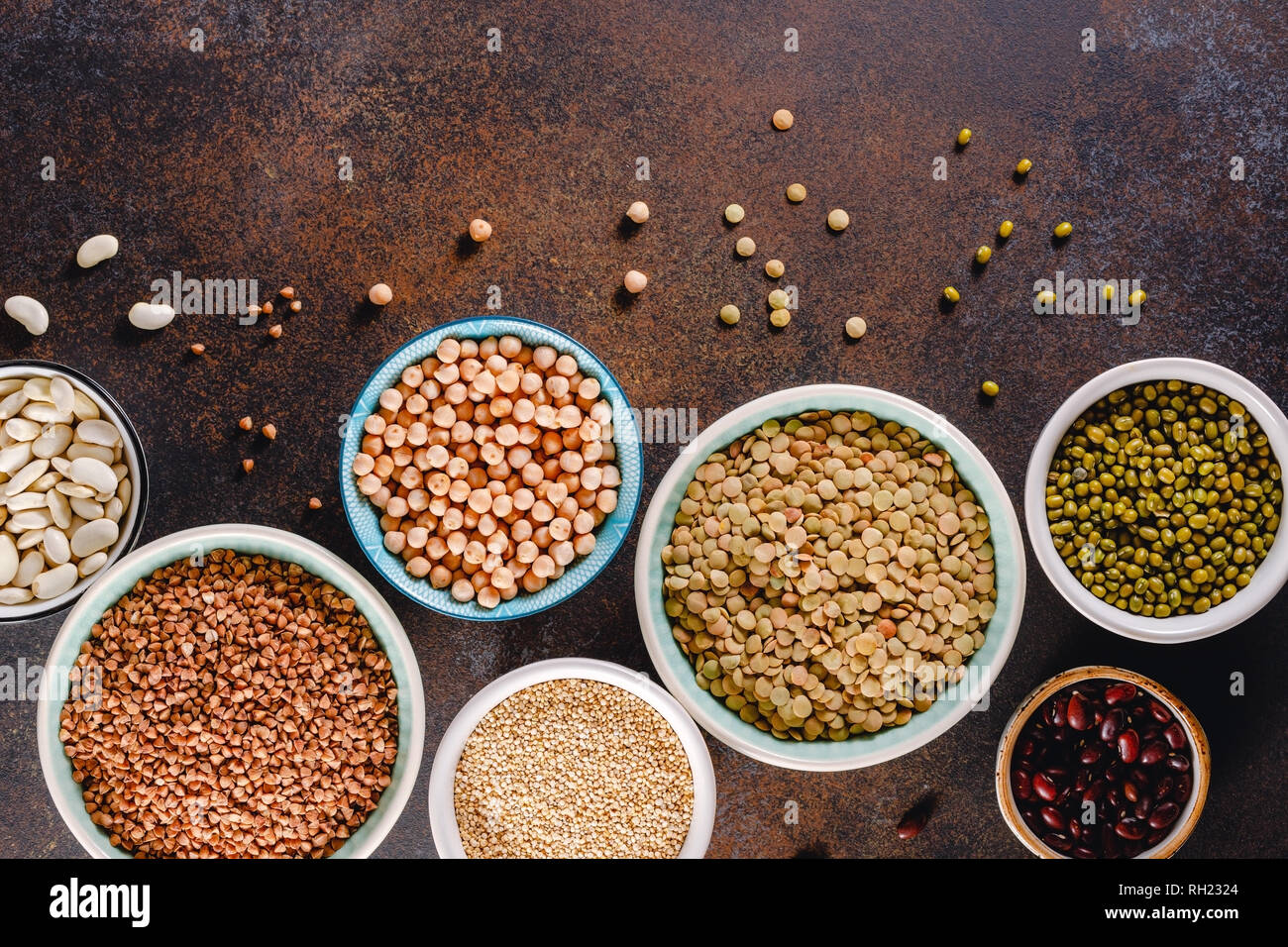 Top view on bowls with various raw grains and seeds on a textured dark ...