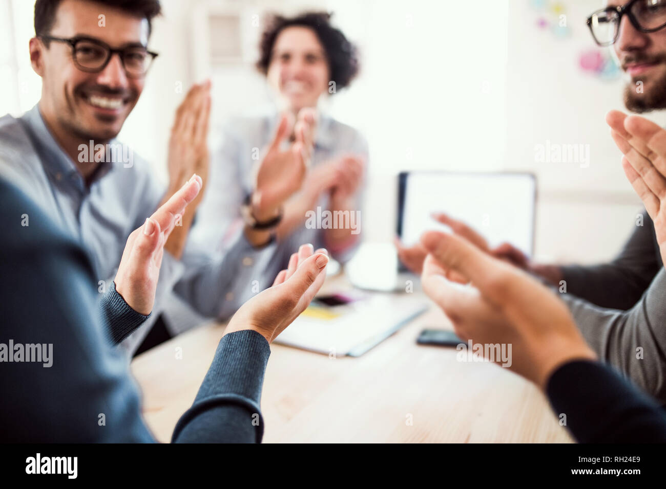 Group of young, cheerful businesspeople sitting around table in a ...