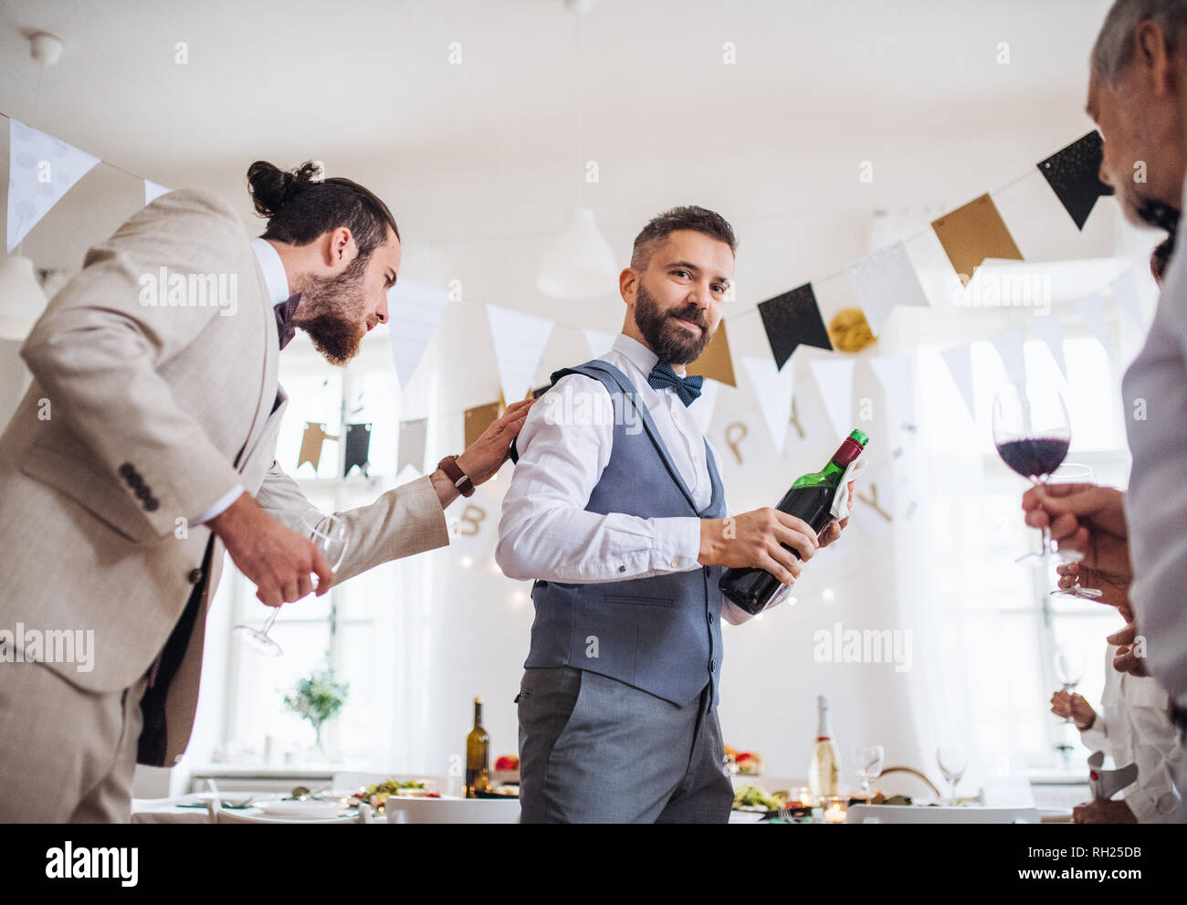 A man pouring happy guests wine on a indoor family birthday party Stock ...