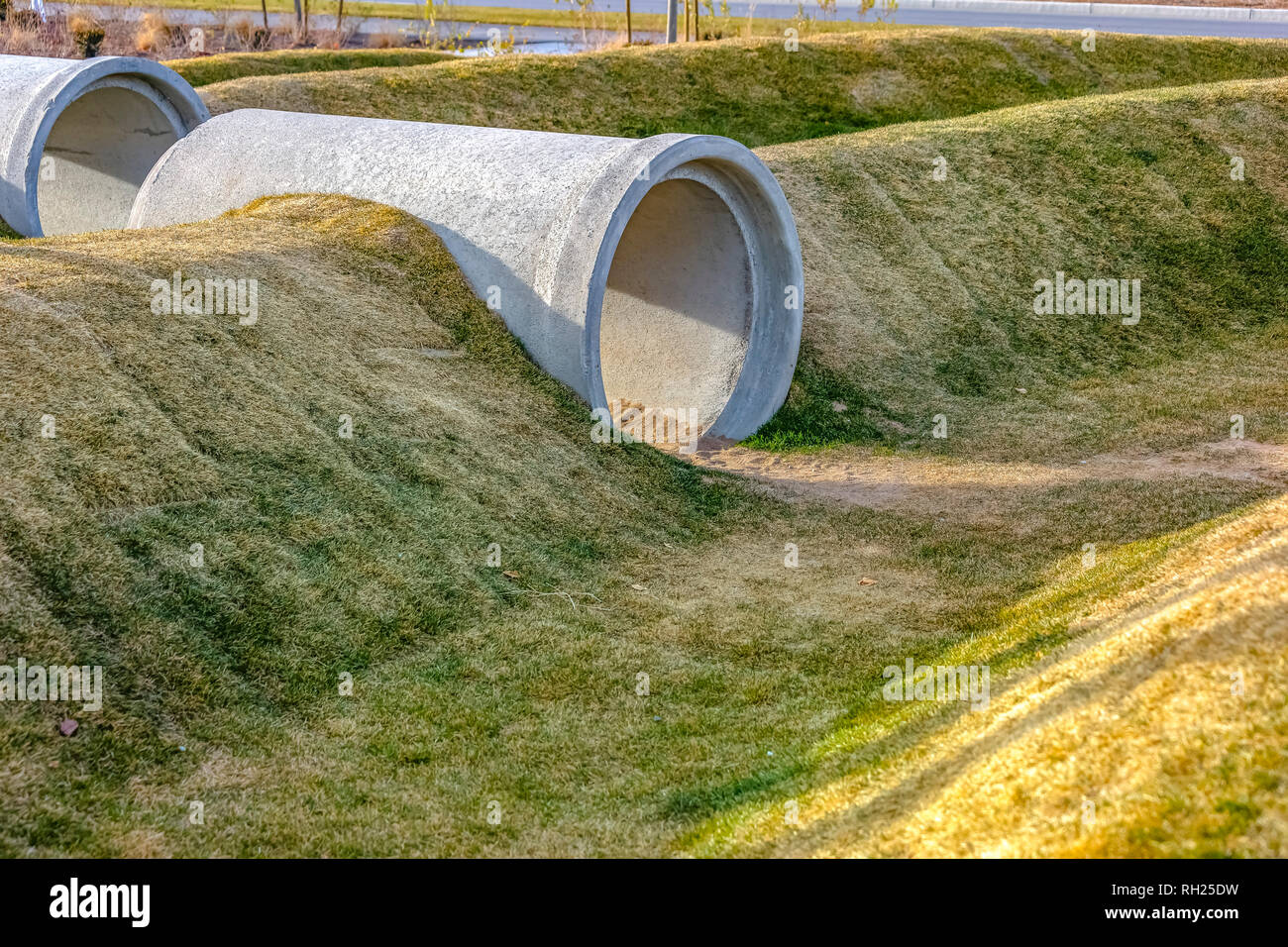 Playground with concrete pipes on grassy slopes Stock Photo - Alamy