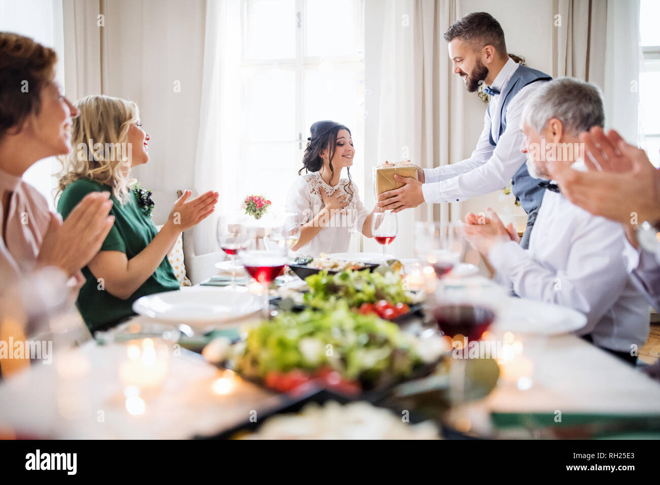 A man giving gift box to a young surprised woman on a family birthday ...
