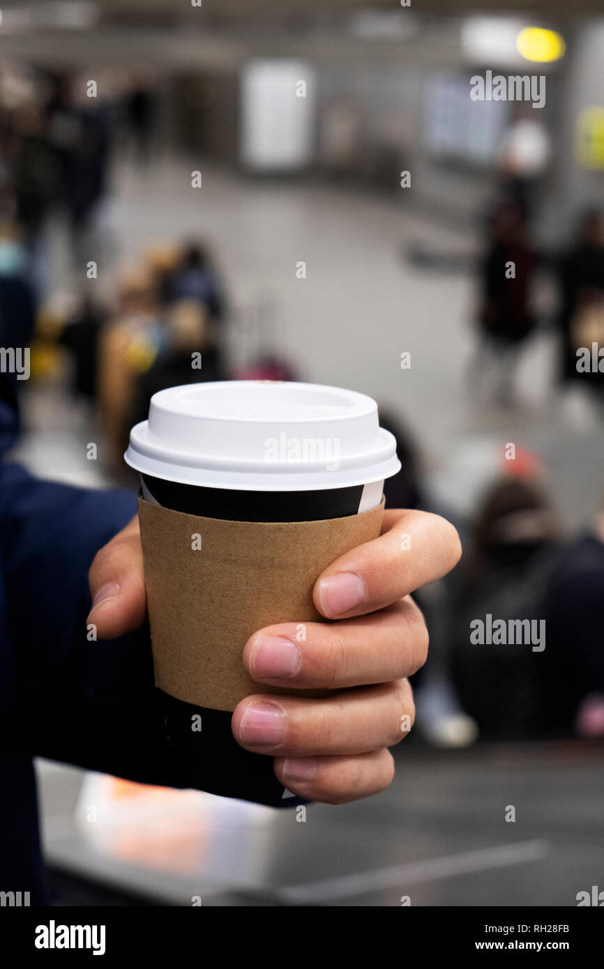 closeup of a young man having a takeout cup of coffee in a subway ...