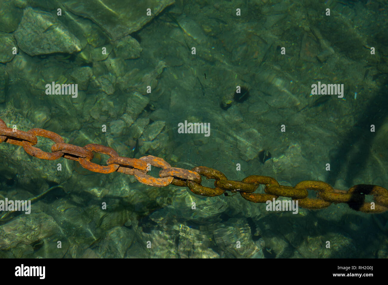 Old massive rusty chain dipping into clear sea water in harbor Stock ...