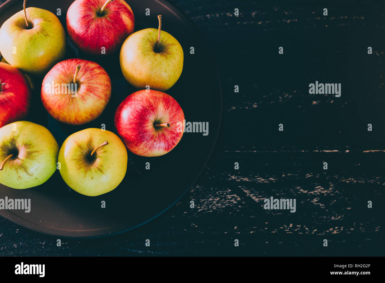 group of organic mixed colours red green and yellow apples on dark ...