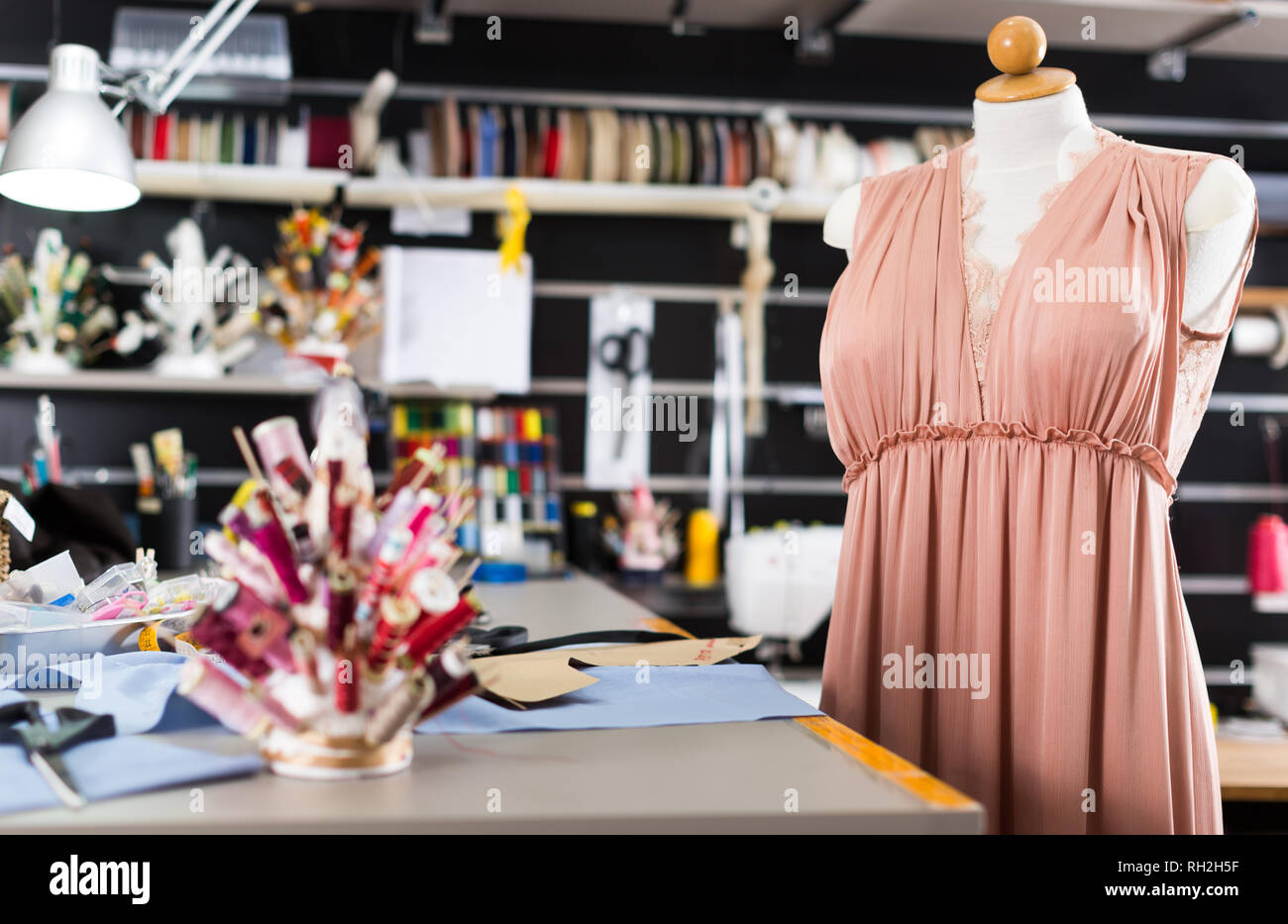 Workplace with mannequin with dress in sewing shop of variety clothes ...