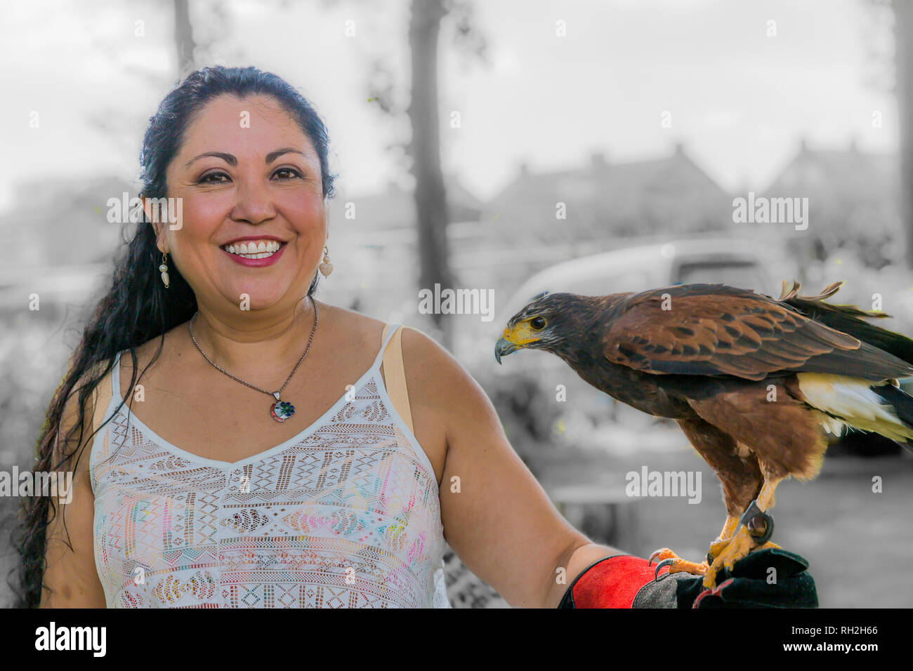 Beautiful smiling woman posing with an eagle hawk in her hand on a ...