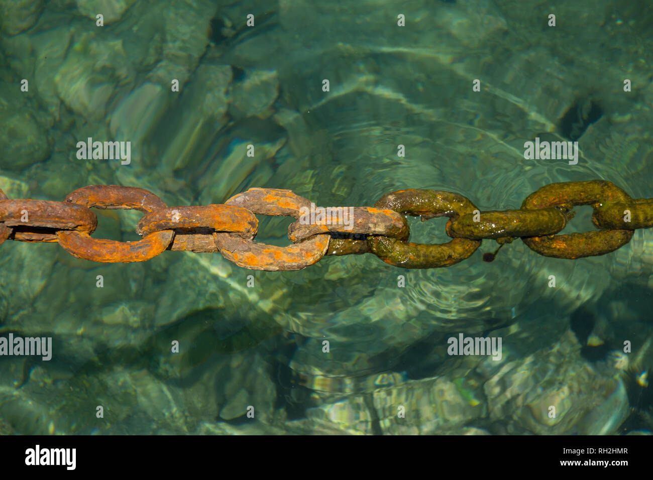 Old massive rusty chain dipping into clear sea water in harbor Stock ...