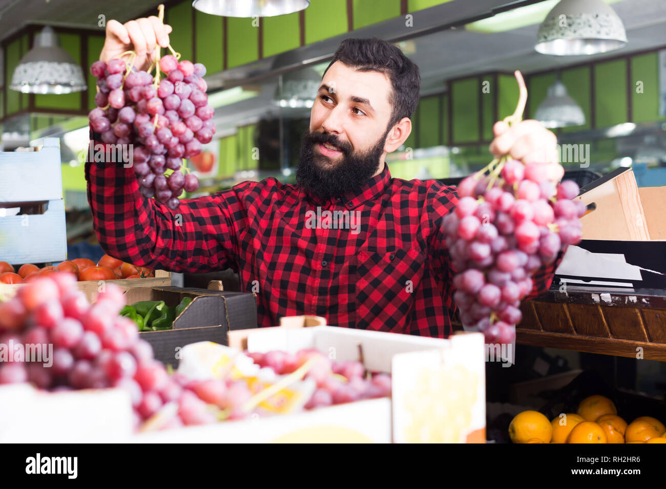 Cheerful male seller offering grapes in grocery shop Stock Photo - Alamy
