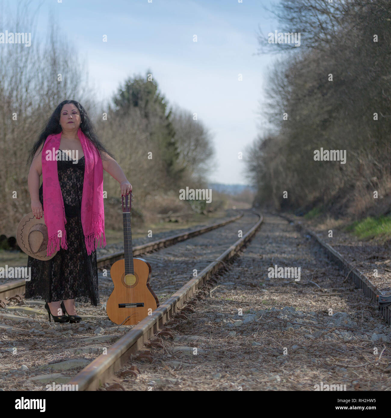 beautiful woman with black dress standing on the train tracks with a ...