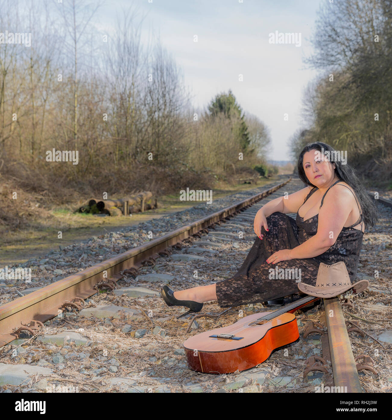 beautiful woman sitting on the train tracks looking and thinking with a ...