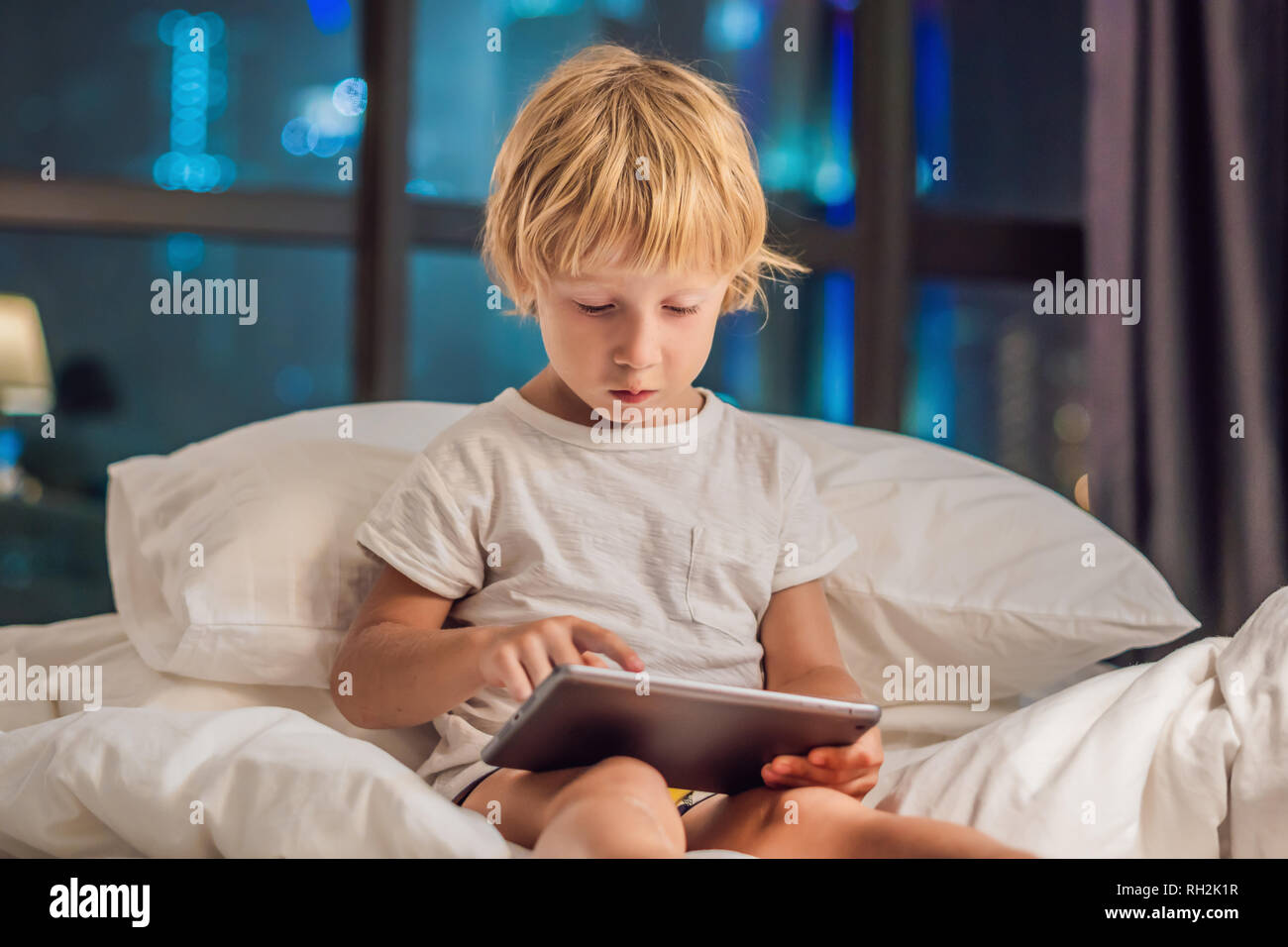 The boy uses the tablet in his bed before going to sleep on a ...