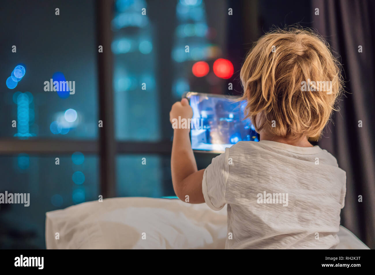 The boy uses the tablet in his bed before going to sleep on a ...