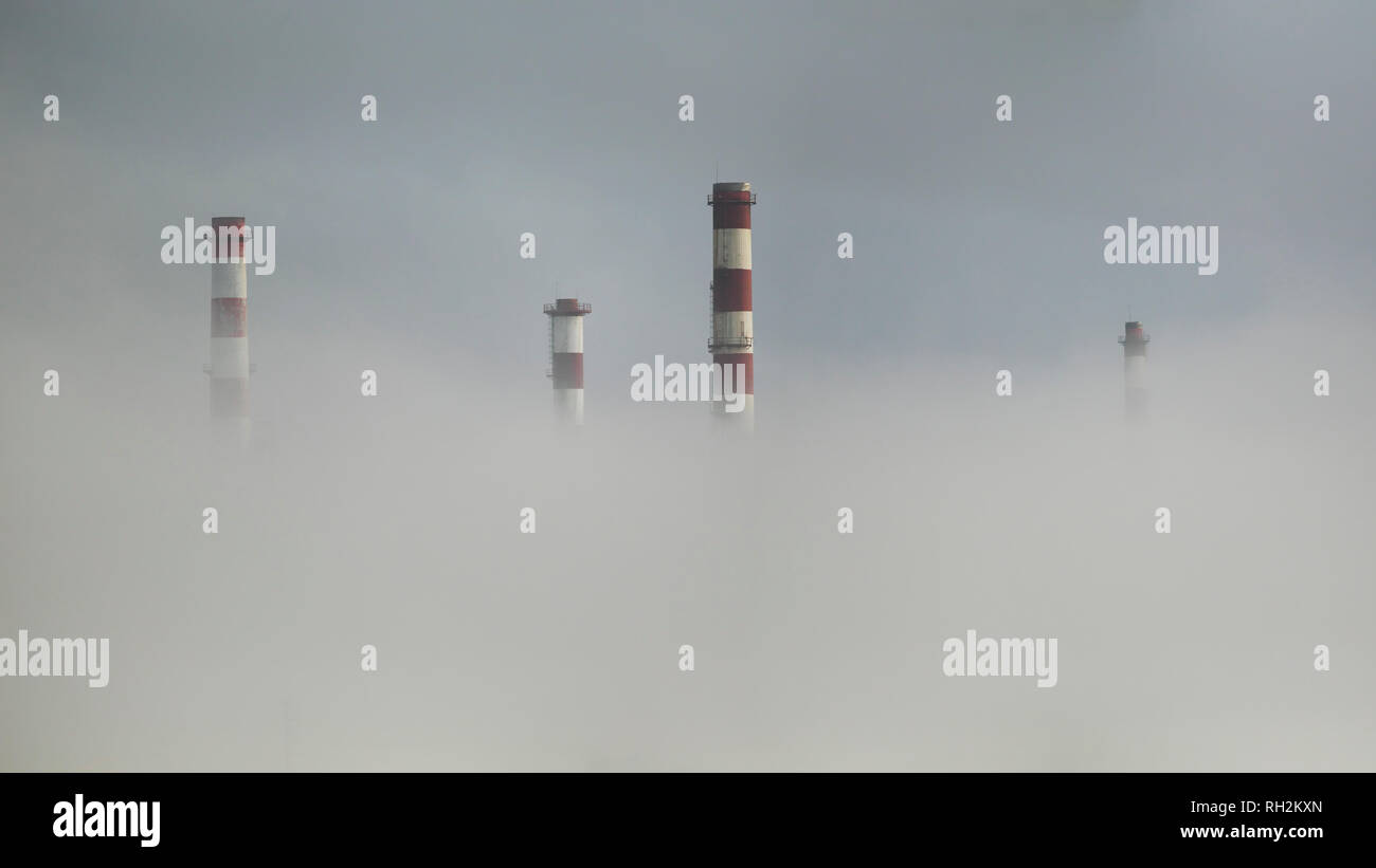 Oil refinery chimneys semi losted in the fog Stock Photo - Alamy