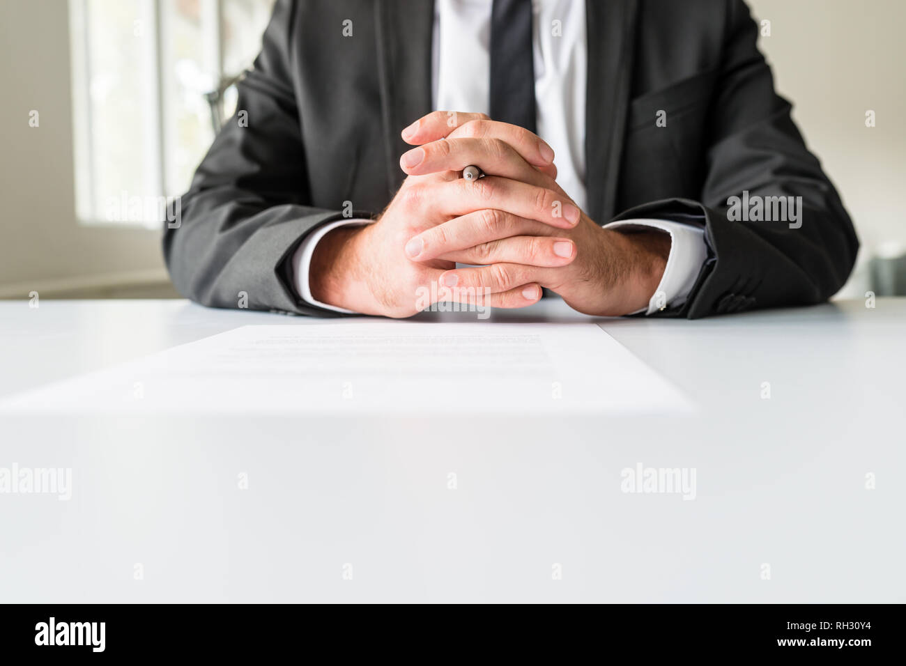 Front view of businessman sitting at his office desk with his hands ...