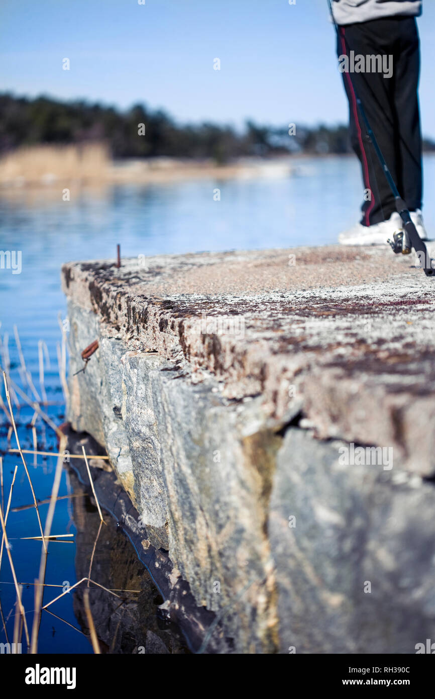 Boy fishing on a concrete jetty Stock Photo - Alamy