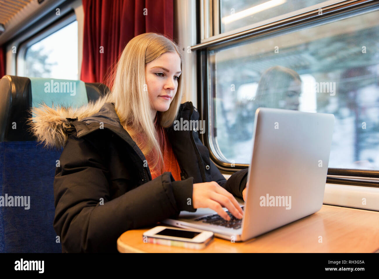 Young woman with laptop in train Stock Photo - Alamy