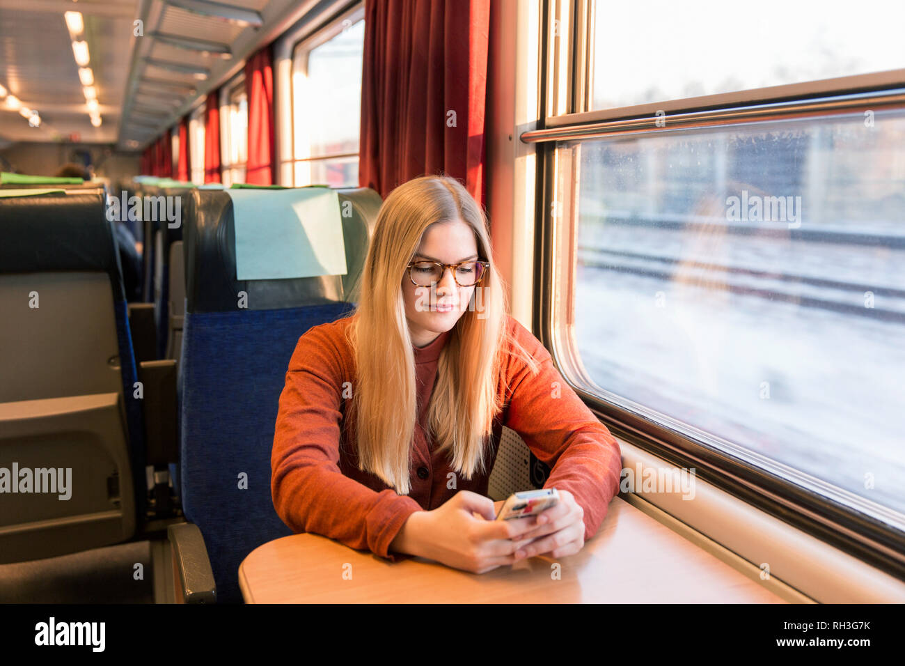 Young woman using cell phone in train Stock Photo - Alamy