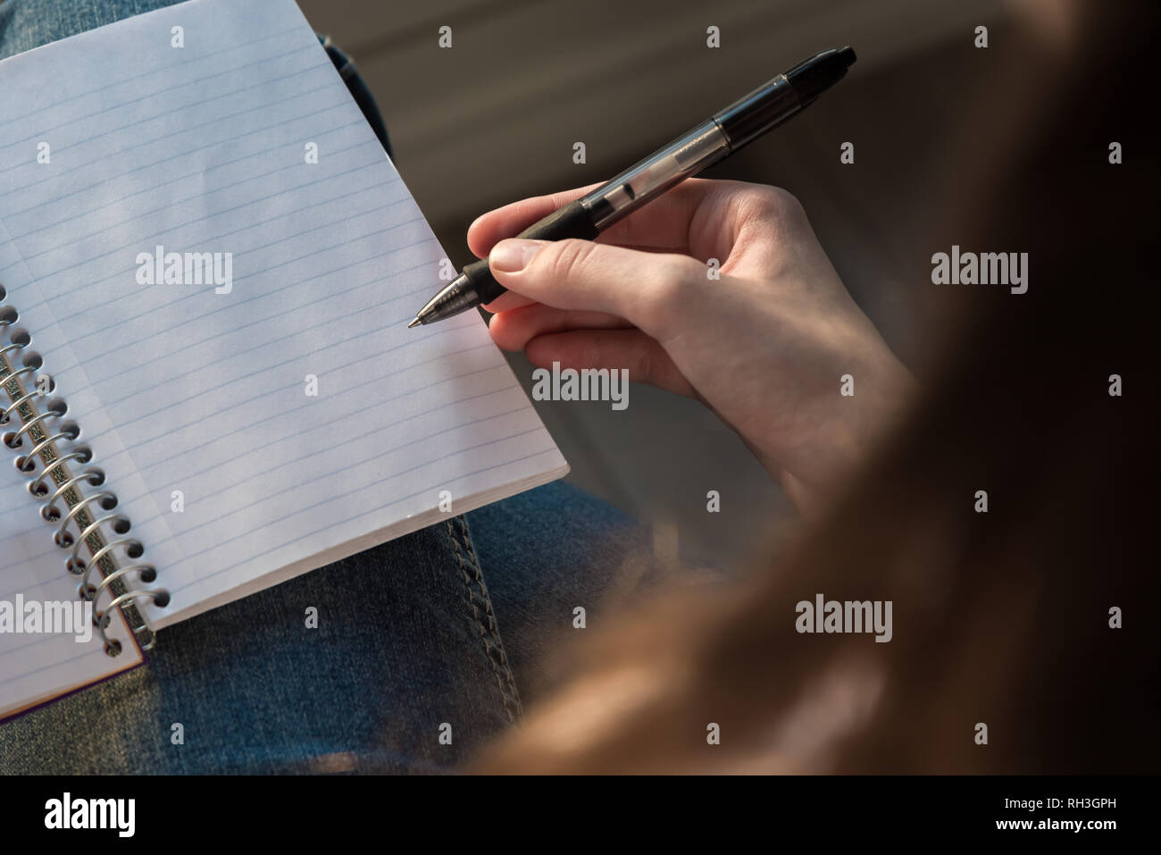 Woman seated with open notebook in lap and holding pen in hand Stock ...