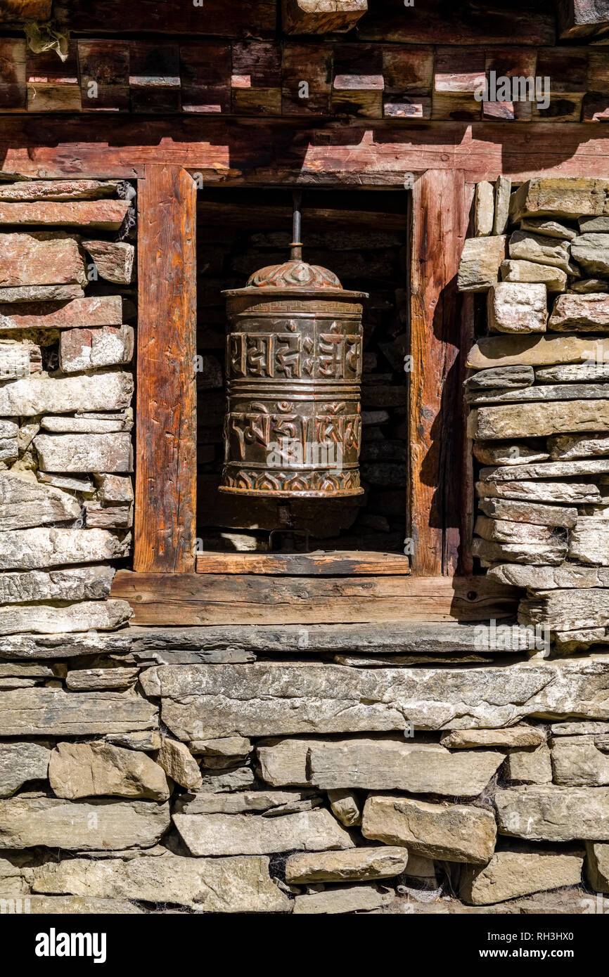 Prayer wheel placed in the facade of a traditional stone house of the ...