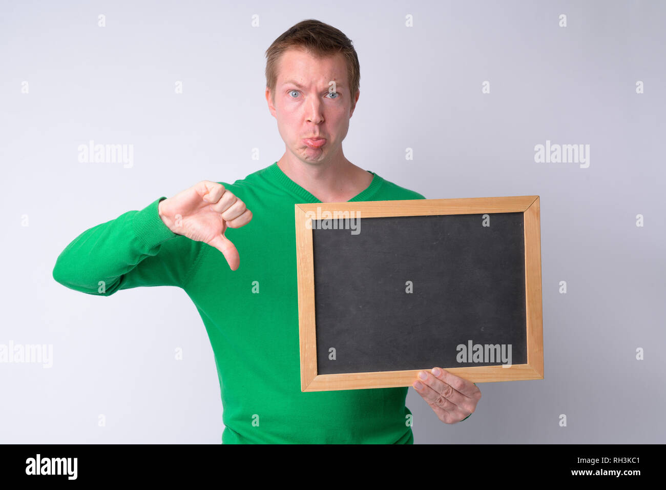 Young sad man holding blackboard and giving thumbs down Stock Photo - Alamy