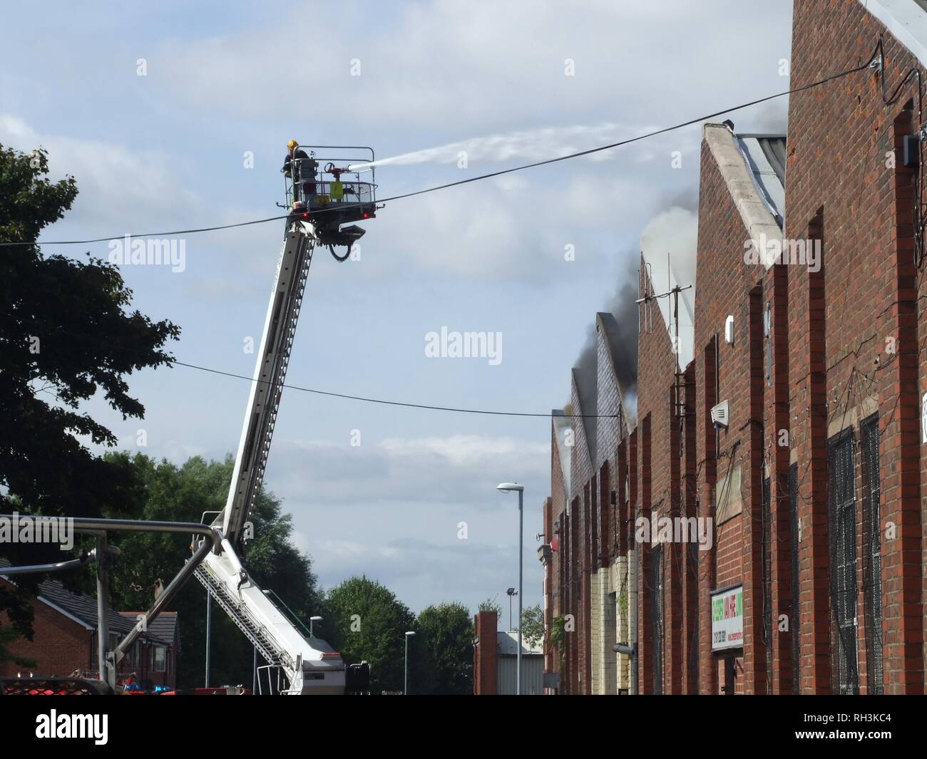 Firefighter directing high pressure water spray at fire inside ...