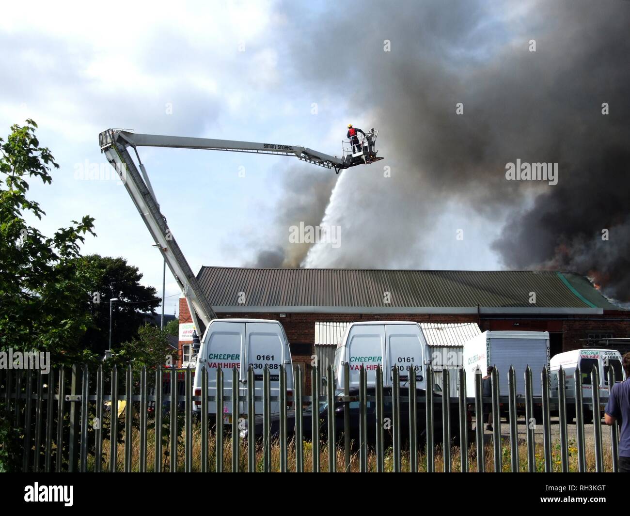 Fire fighter on simon snorkel directing water jet at fire hi-res stock ...