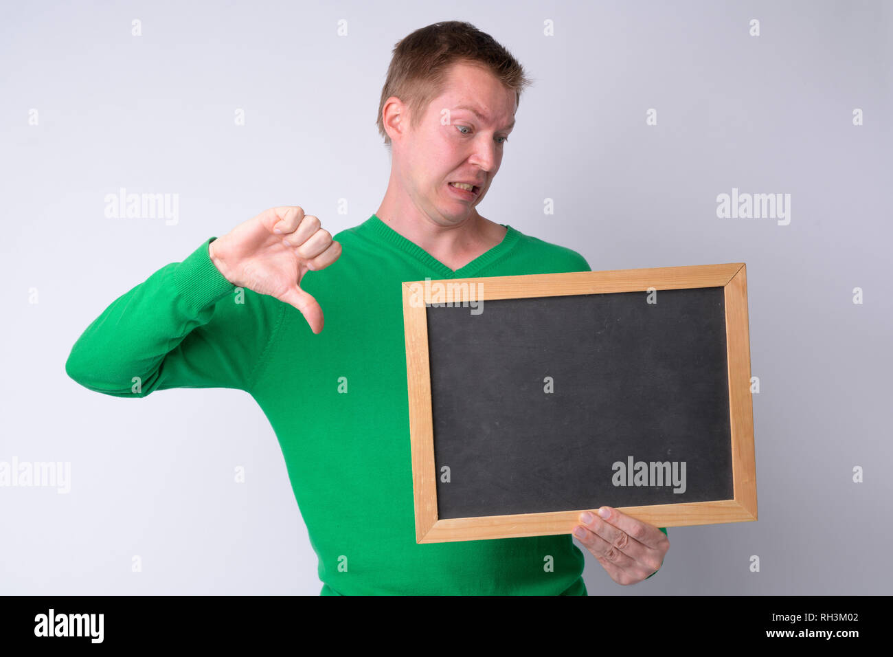 Young stressed man holding blackboard and giving thumbs down Stock ...