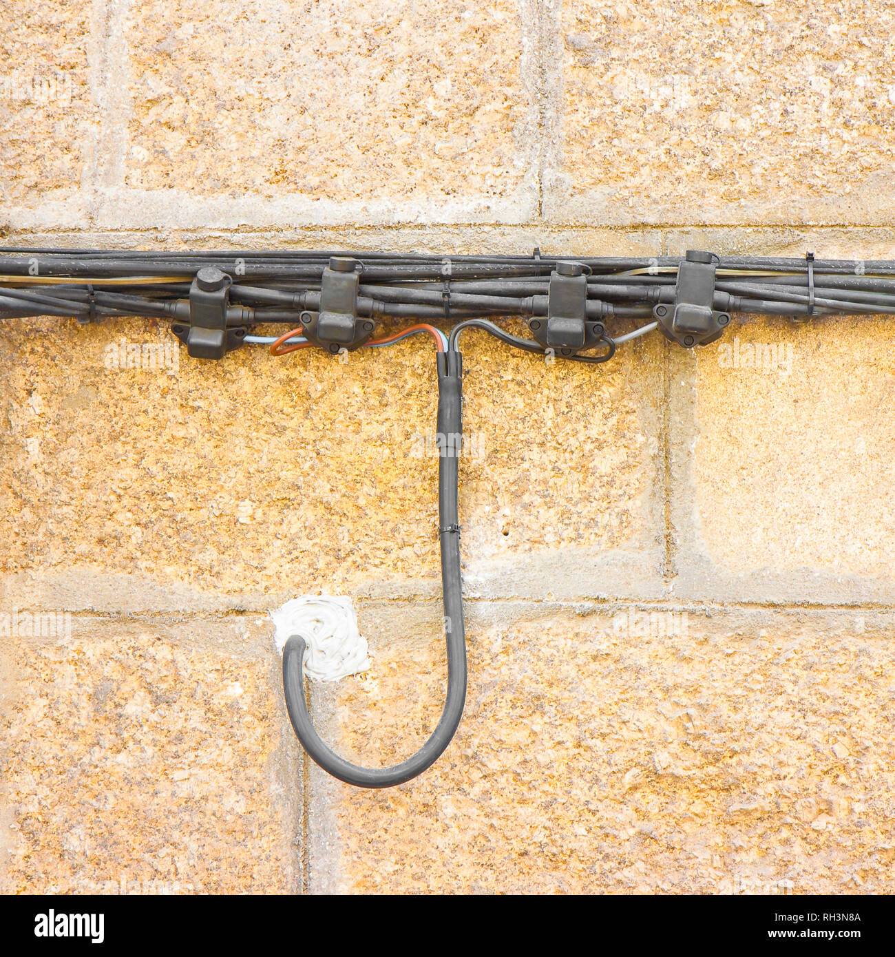 Electrical power cable against a stone wall Stock Photo - Alamy