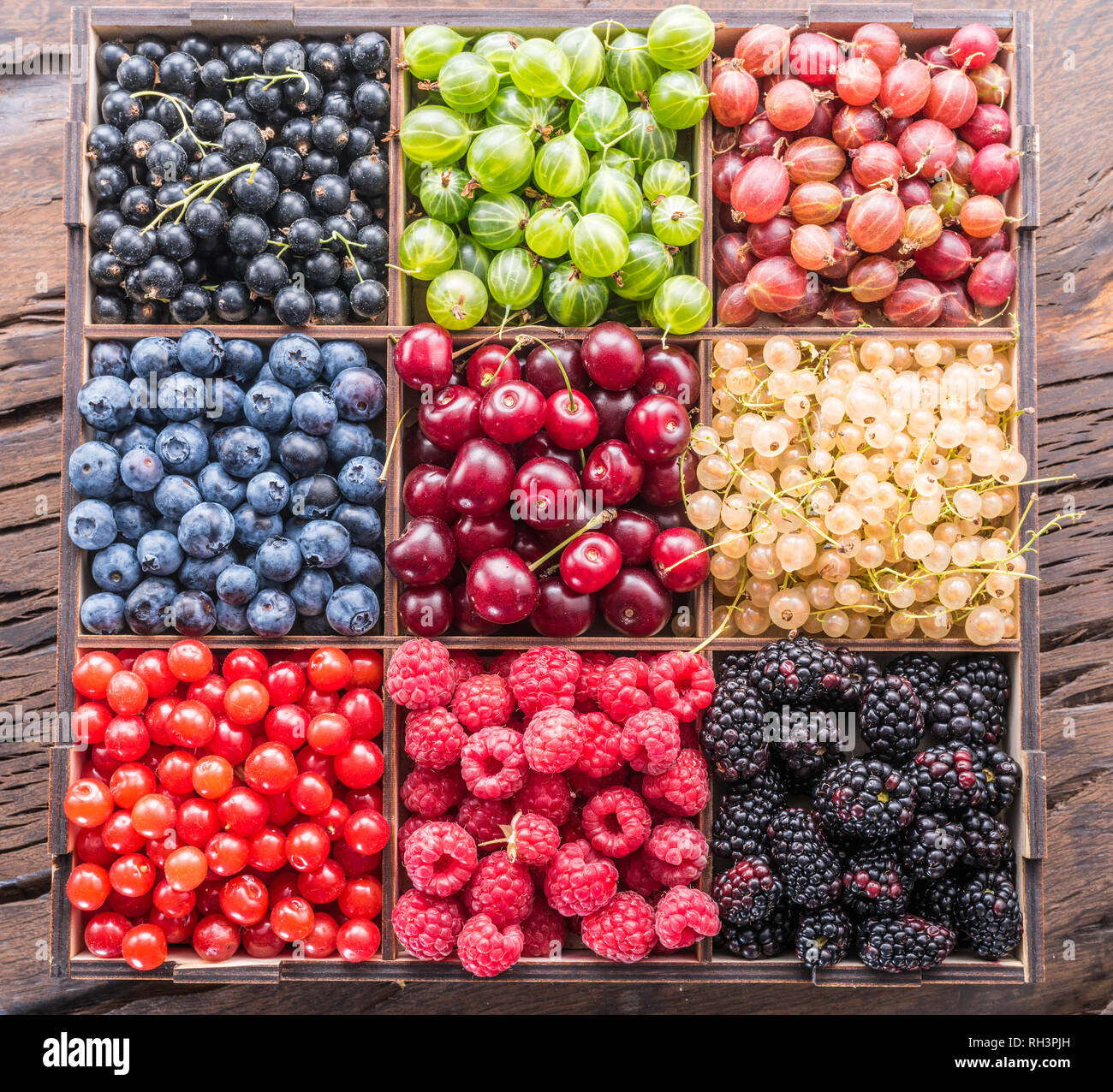 Colorful berries in wooden crate on the table. Top view Stock Photo - Alamy