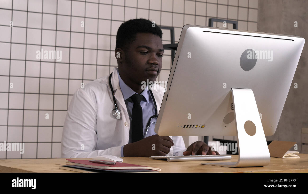 African American doctor at work looking at monitor of his computer ...