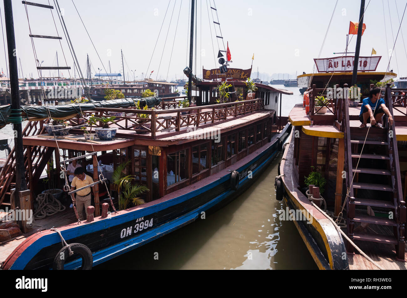 Several wooden cruise ships and junk boats at anchor with crew waiting ...