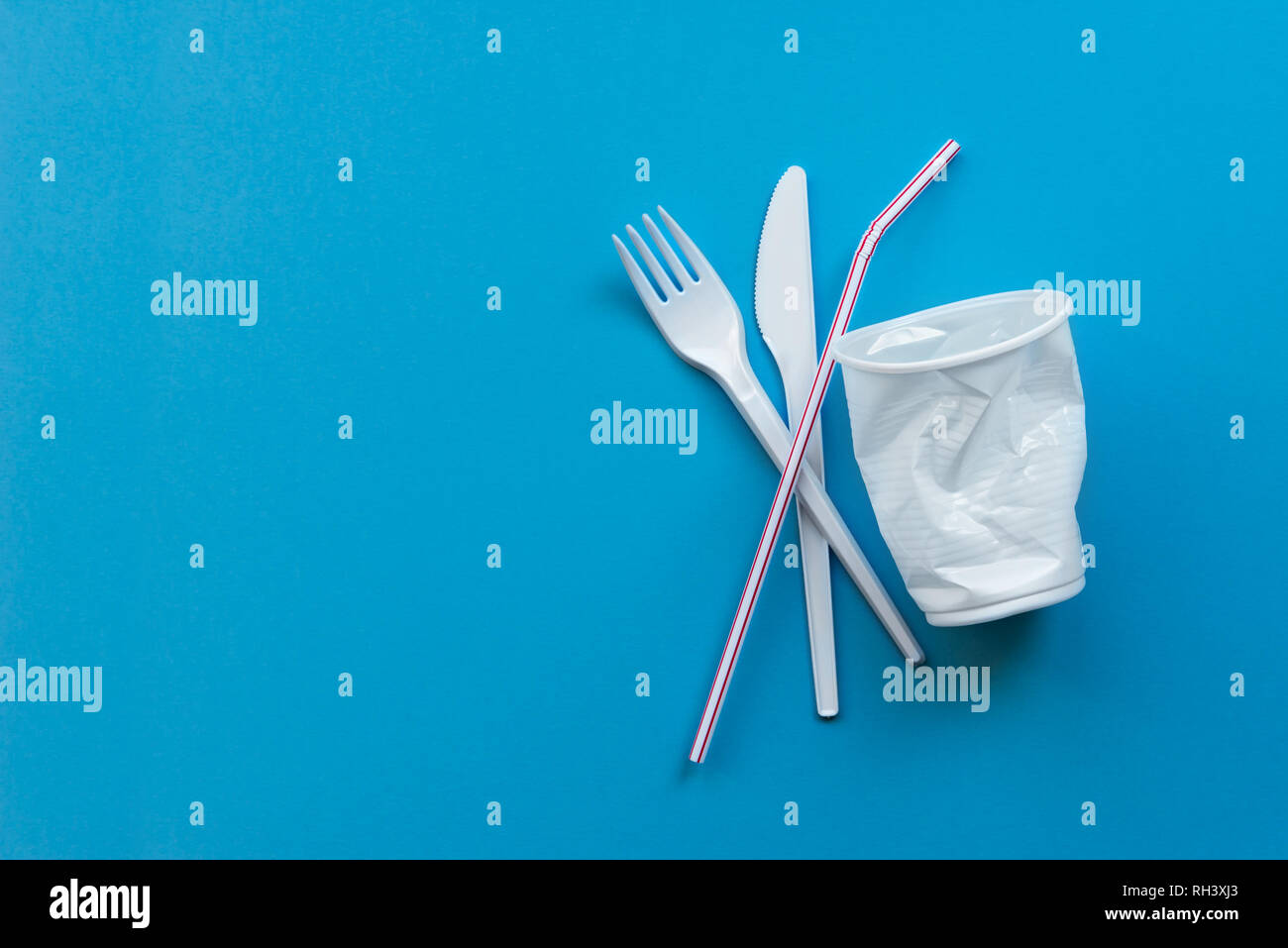 White single-use plastic and plastic drink straws on a blue background ...