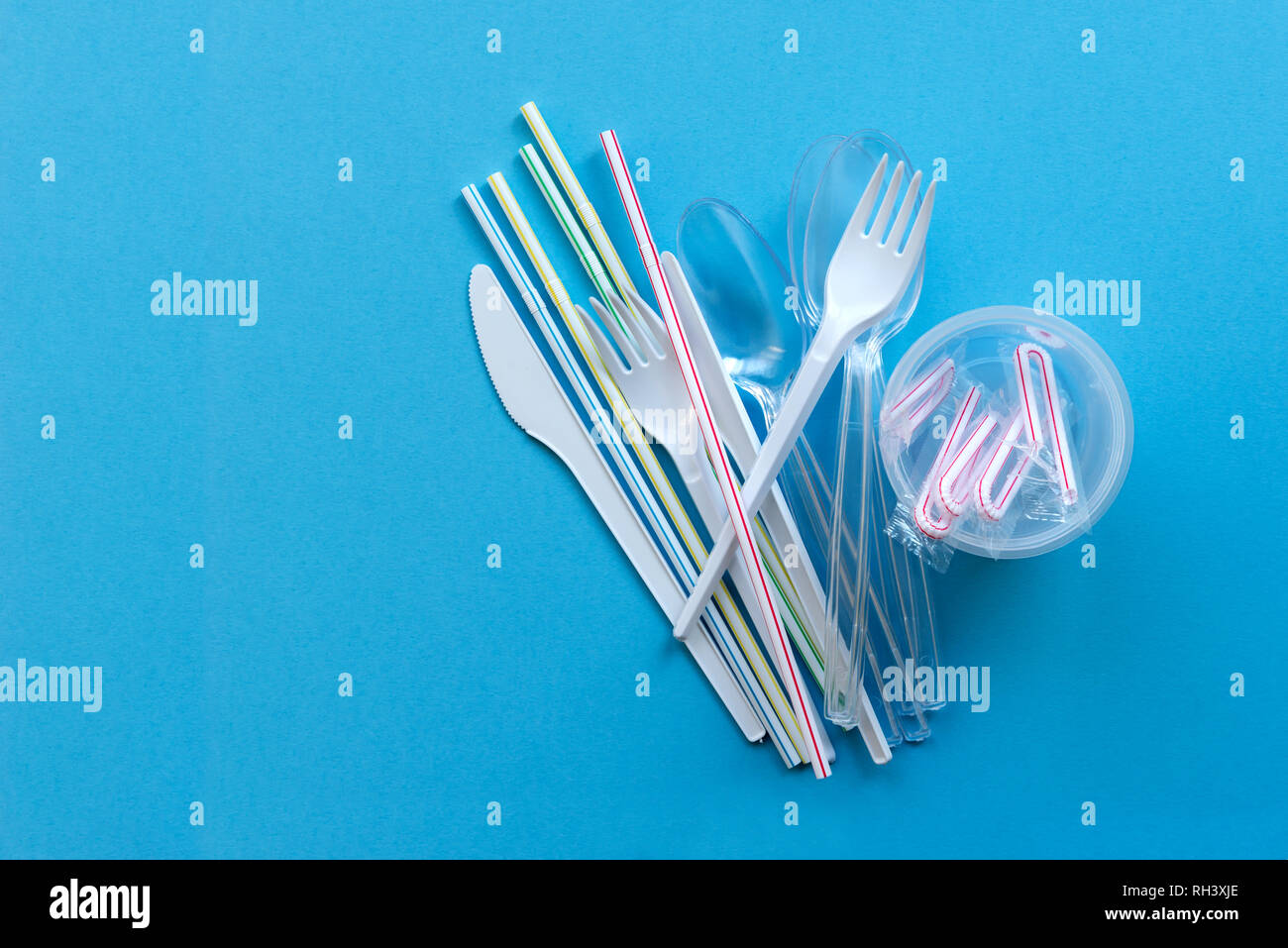 White single-use plastic and plastic drink straws on a blue background ...