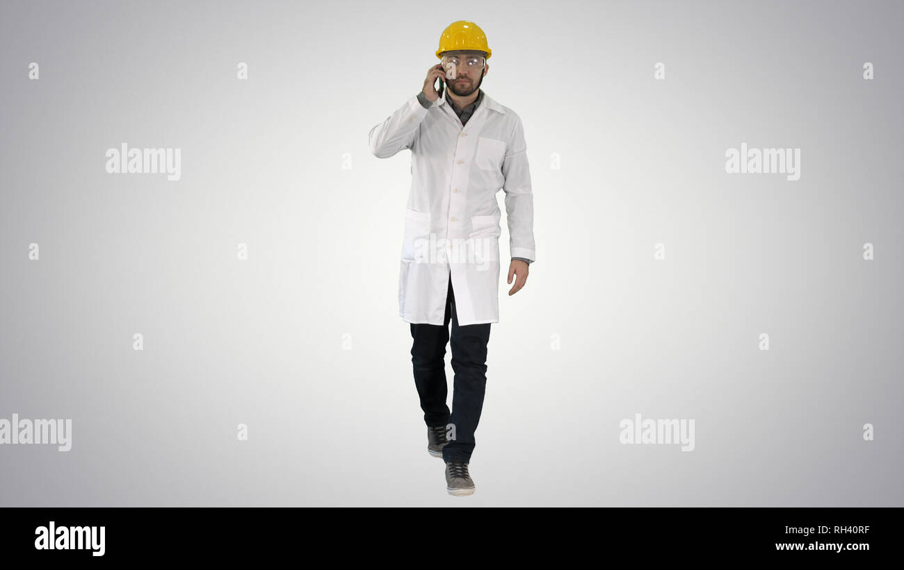 Confident male engineer wearing helmet on call on gradient background ...