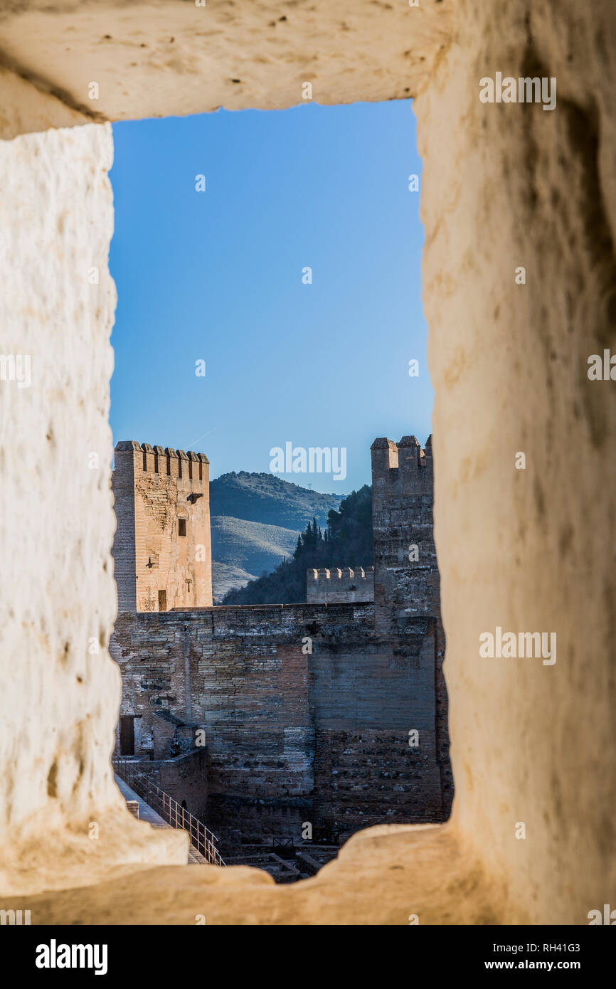View of a brick wall and a tower in the Alhambra through a stone window ...
