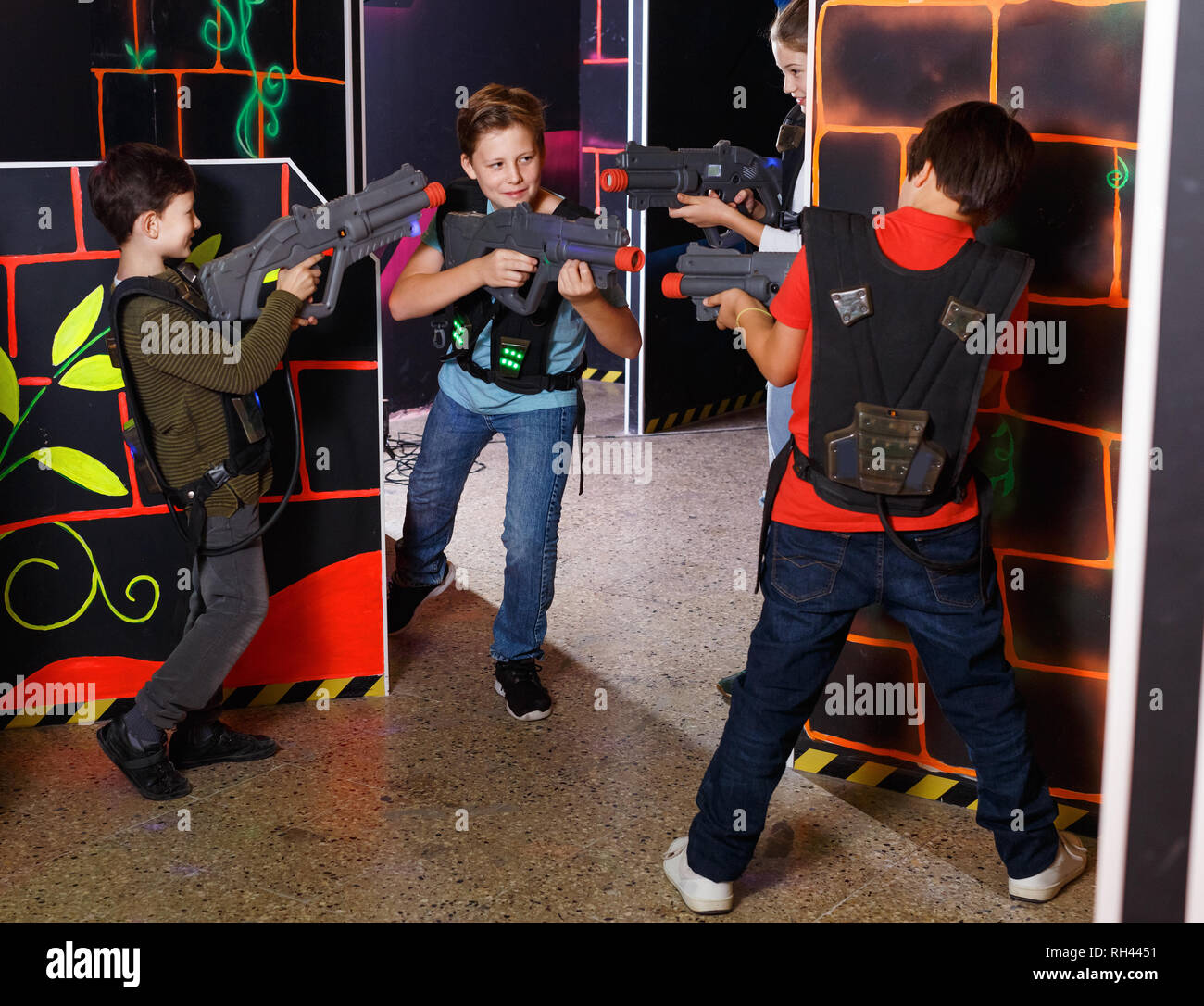 Group of happy smiling teenagers with laser guns having fun on dark ...