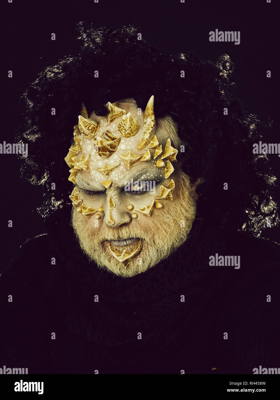 Monster man with white eyes in black wig frowning face on dark ...