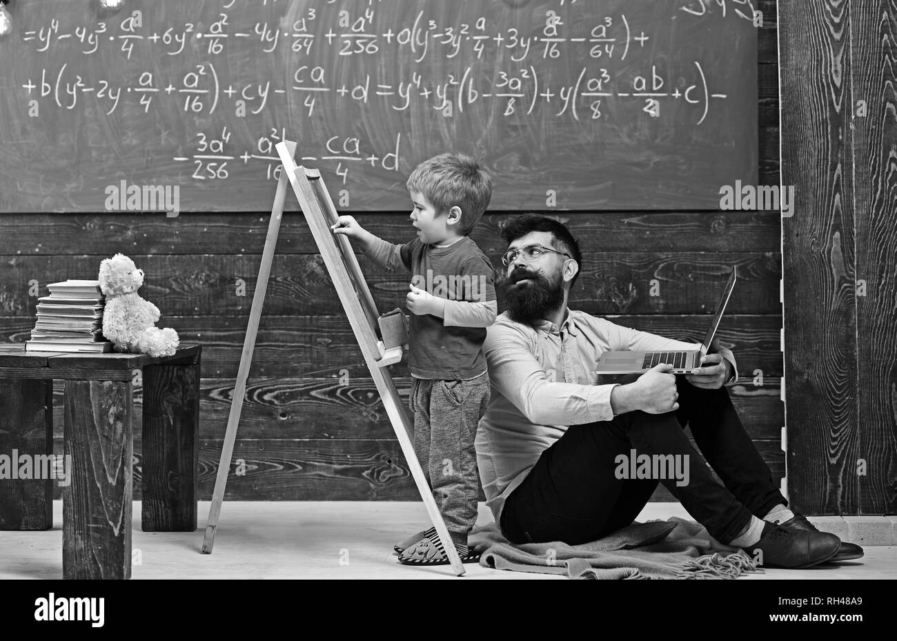 Teacher with long beard checks student writing on chalkboard. Pupil ...