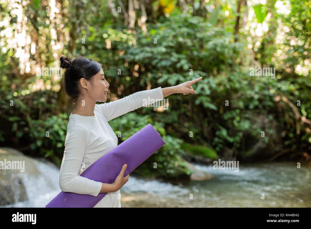 Women wearing a white yoga dress are rolling yoga at the waterfall ...