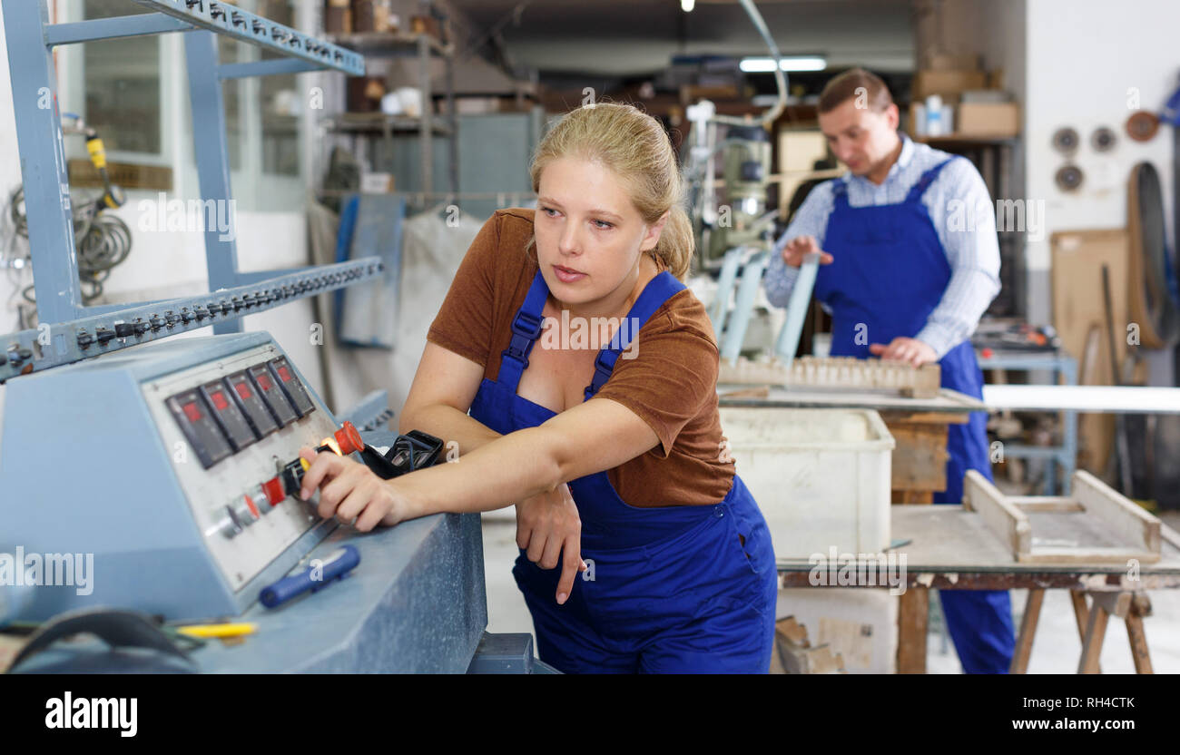 Experienced female worker of glass factory engaged in adjustment of ...