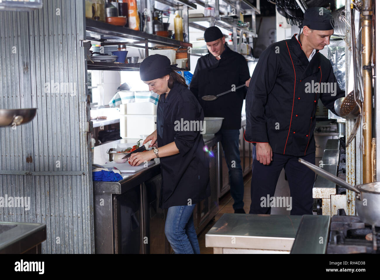 Friendly cooks in process of cooking dishes at restaurant kitchen Stock ...
