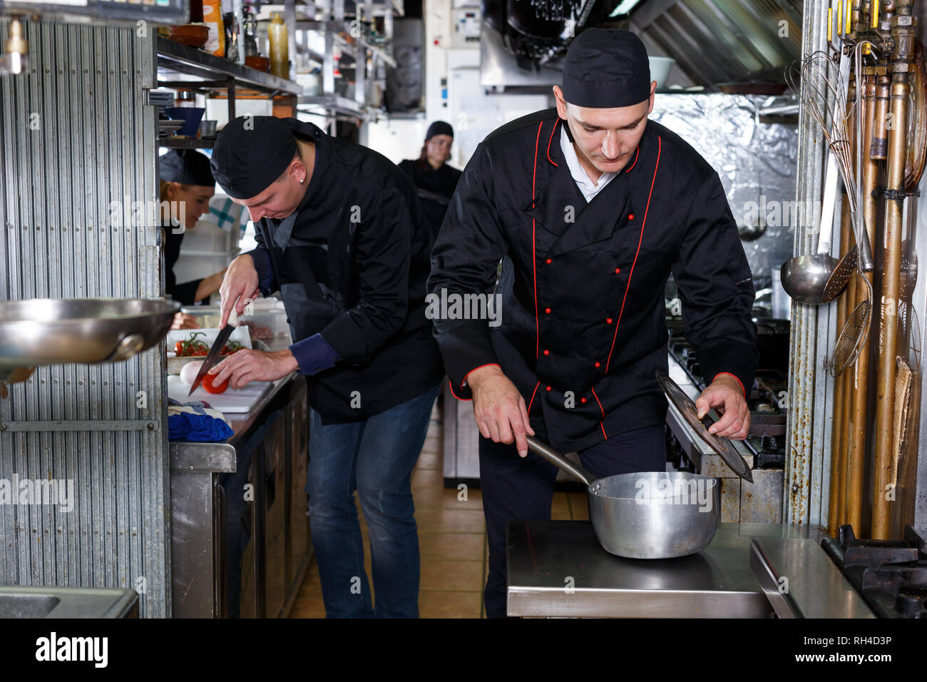 Cheerful cooks dressed in black uniform at restaurant kitchen Stock ...