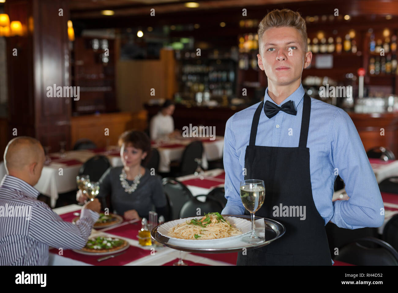 Handsome elegant waiter with serving tray welcoming to restaurant Stock ...