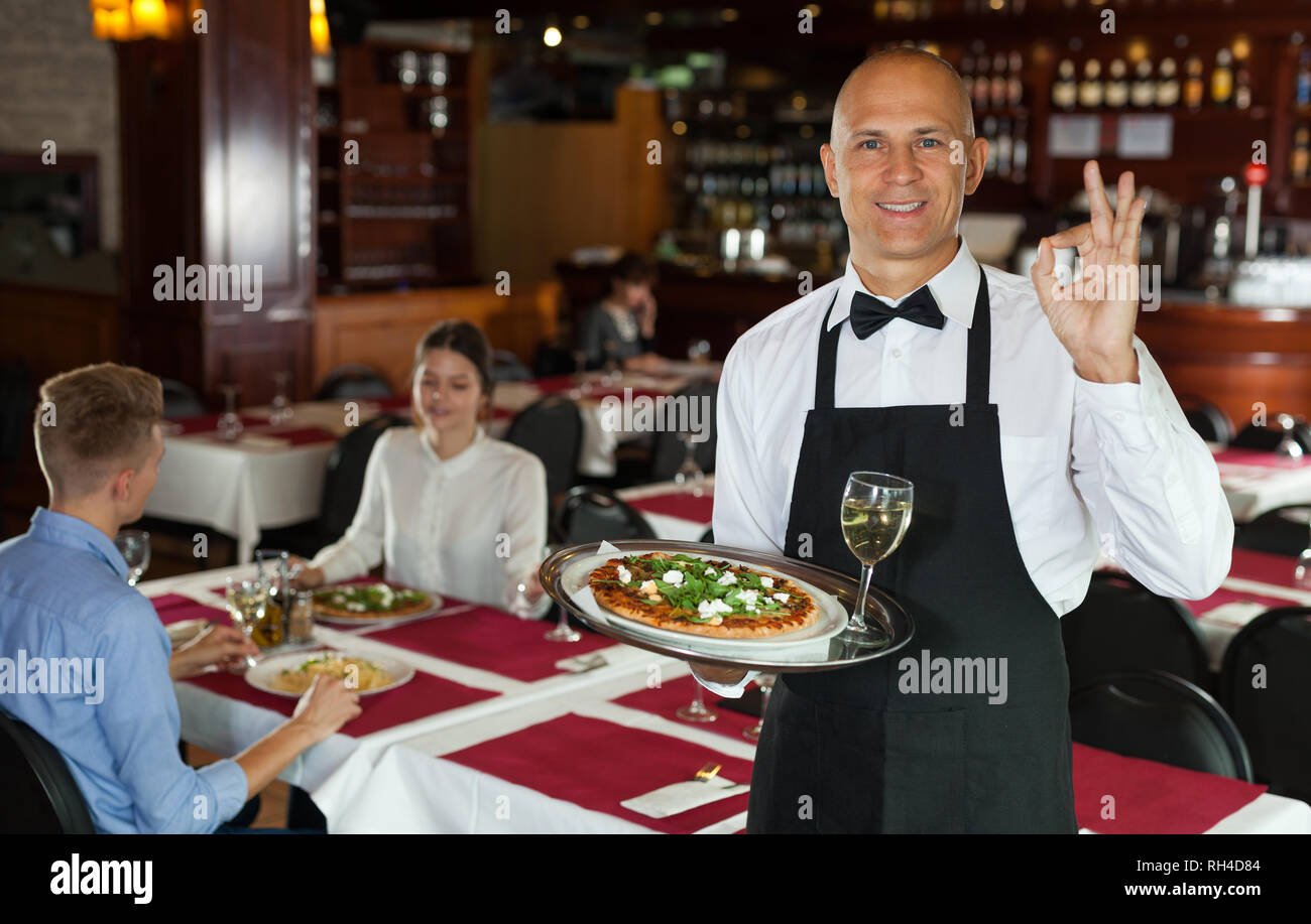 Handsome elegant waiter with serving tray welcoming to restaurant Stock ...